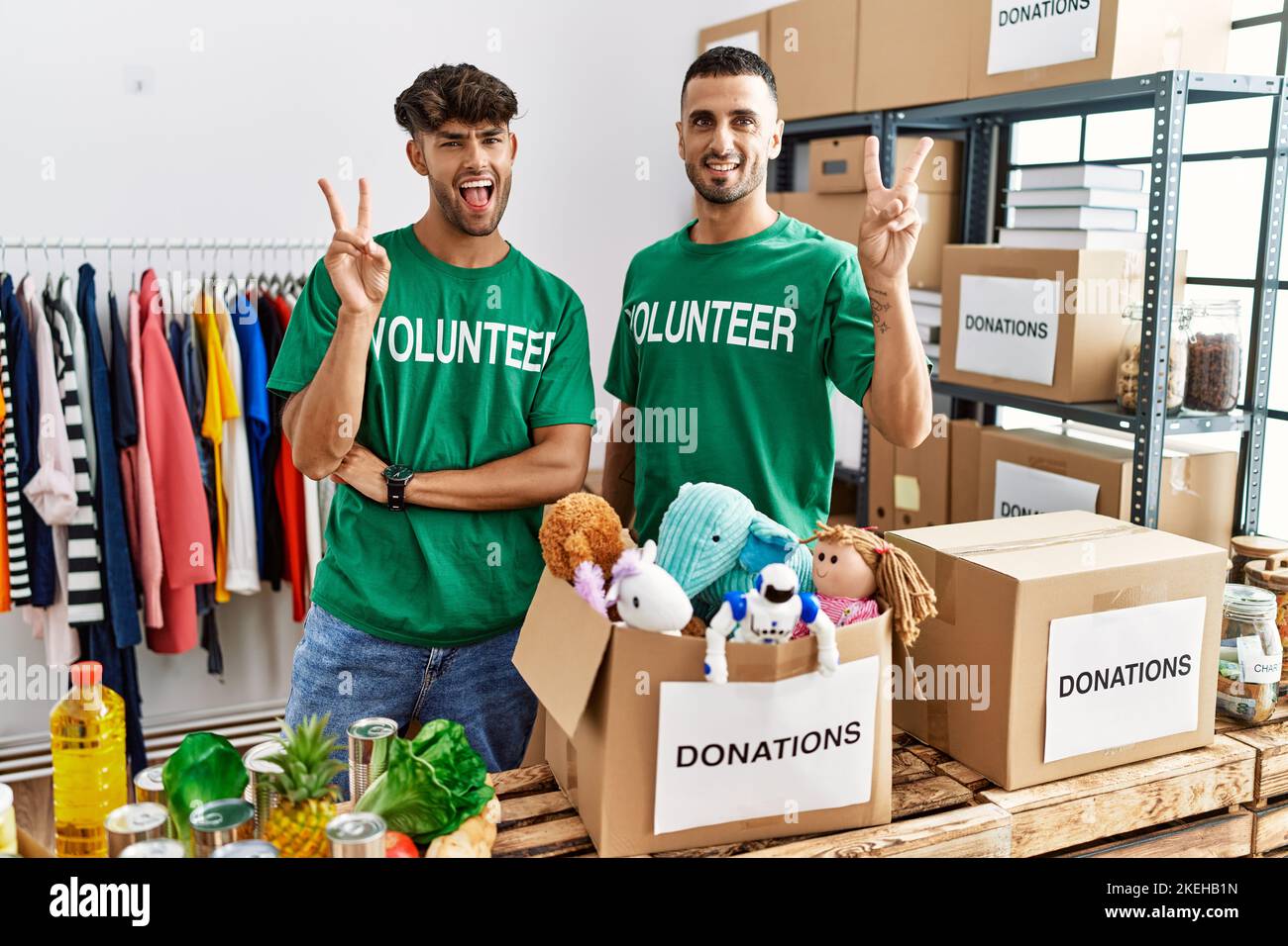 Young gay couple wearing volunteer t shirt at donations stand smiling ...
