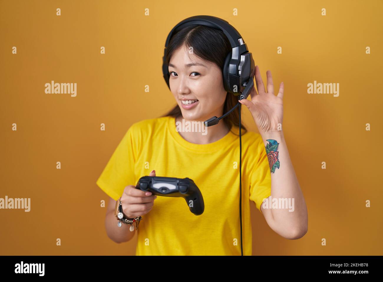 Chinese young woman playing video game holding controller smiling with ...