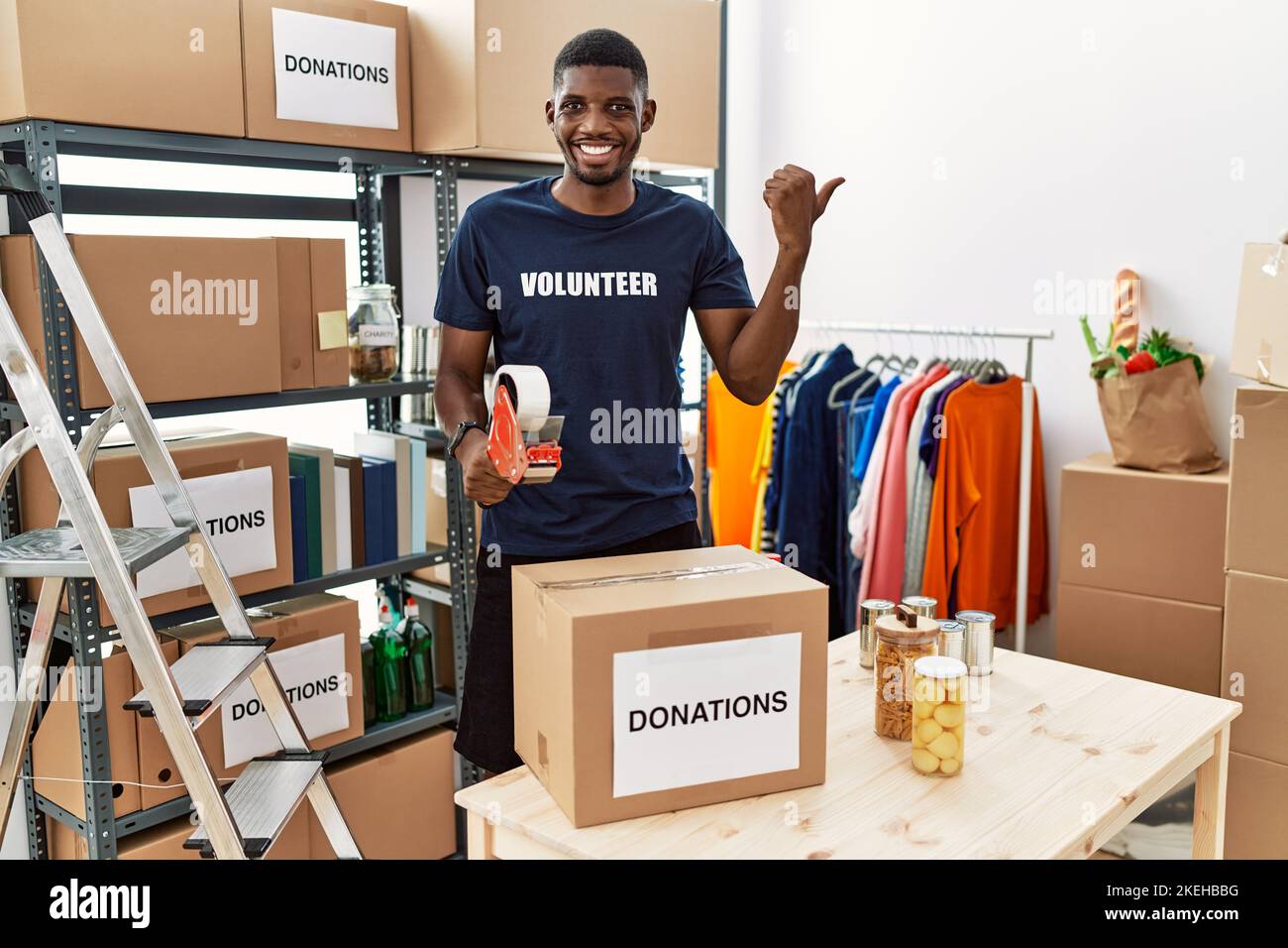 Young african american volunteer man packing donations box for charity ...