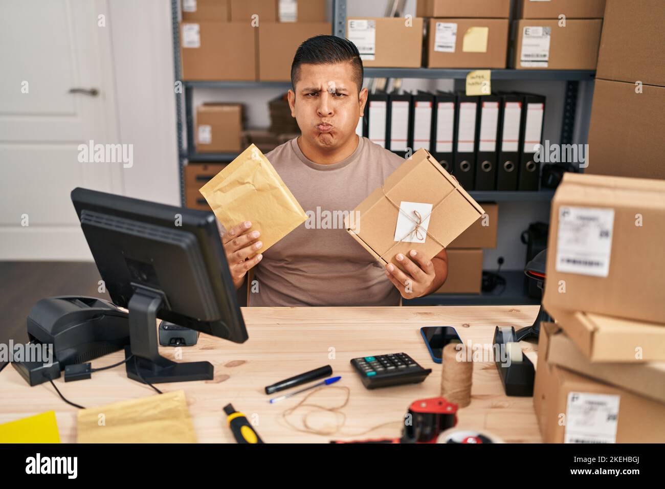 Hispanic young man working at small business ecommerce holding packages ...