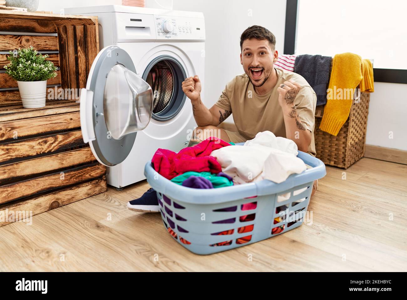 Young handsome man putting dirty laundry into washing machine ...