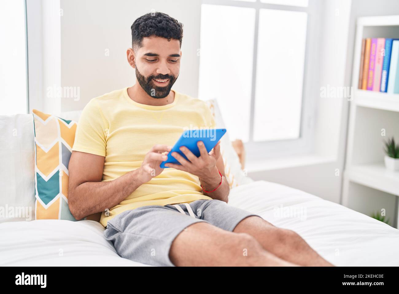 Young arab man using touchpad sitting on bed at bedroom Stock Photo - Alamy