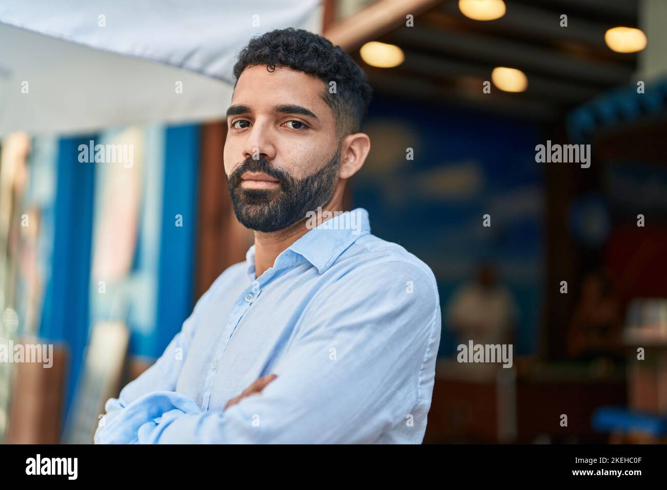 Young arab man standing with serious expression and arms crossed ...
