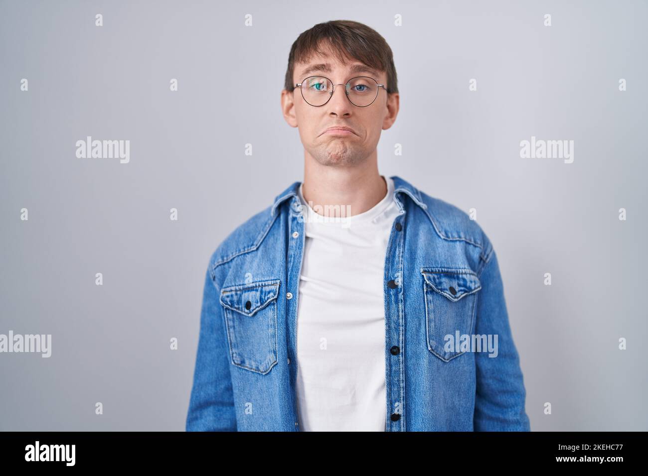 Caucasian blond man standing wearing glasses depressed and worry for ...
