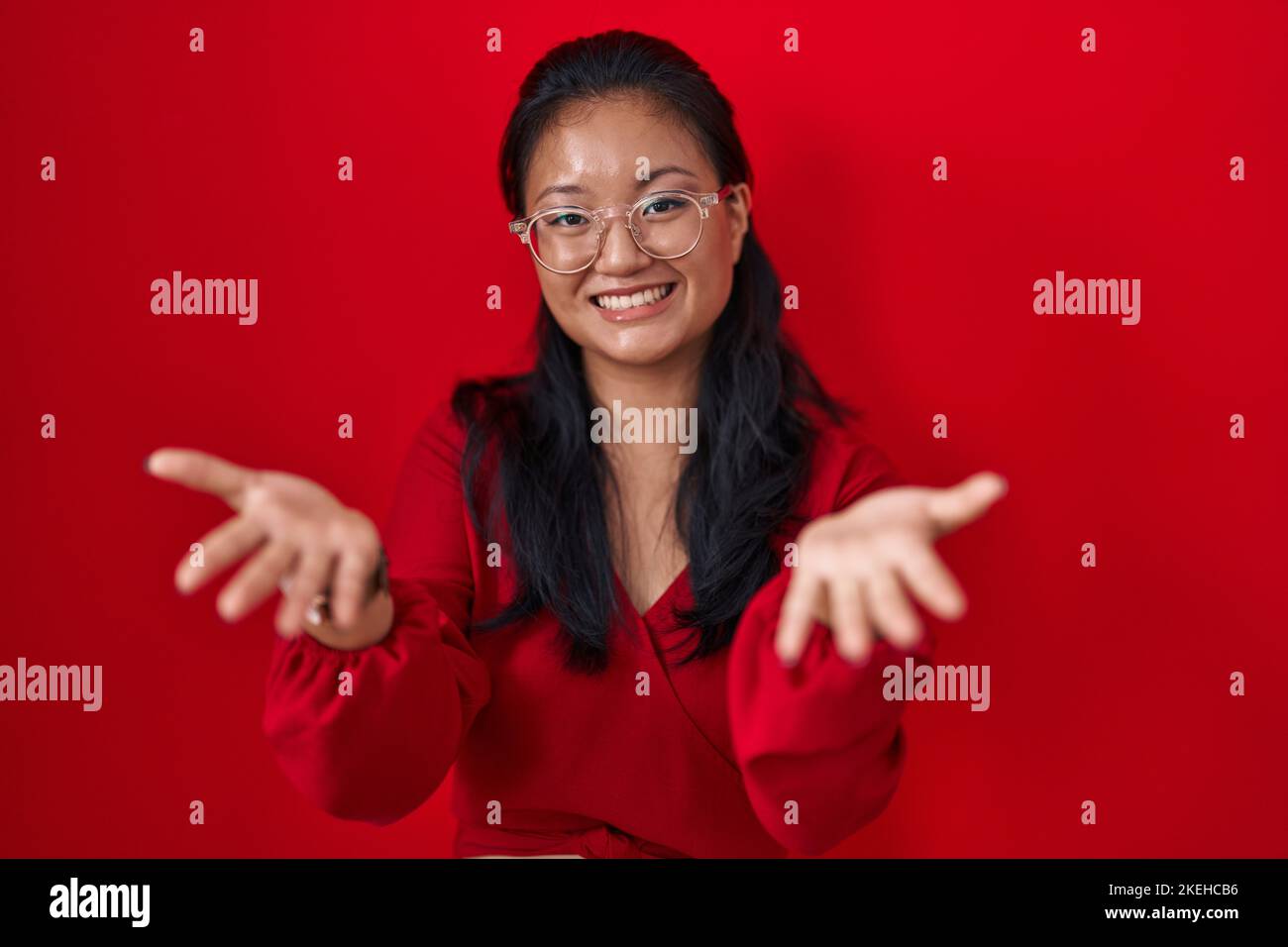 Asian young woman standing over red background smiling cheerful ...