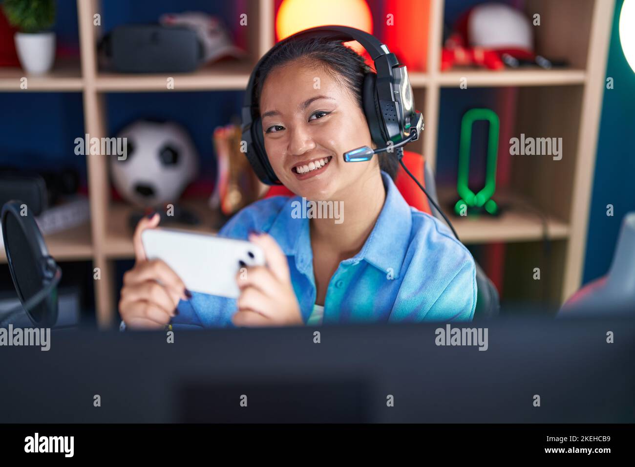 Young chinese woman streamer playing video game using smartphone at ...