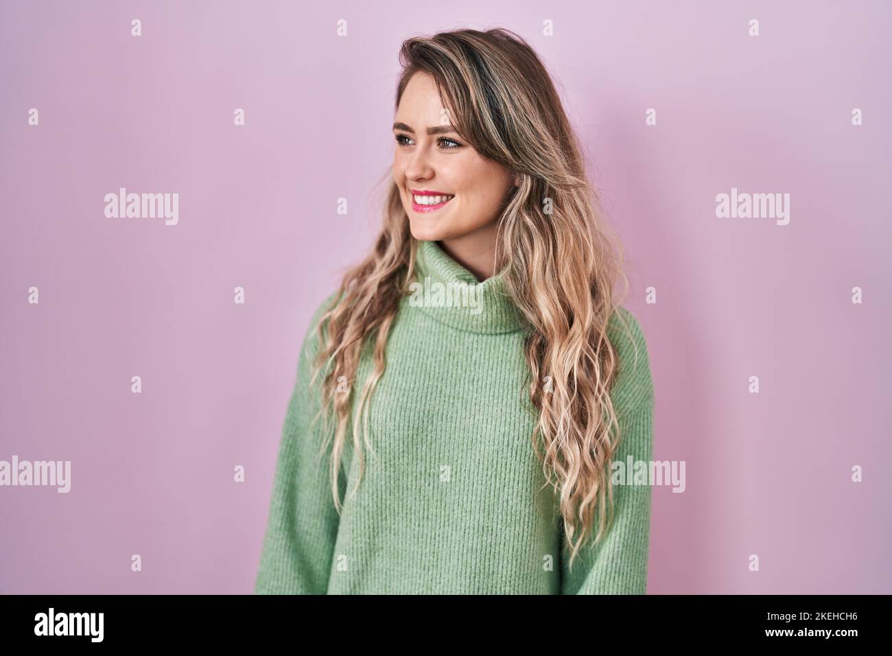 Young caucasian woman standing over pink background looking away to ...