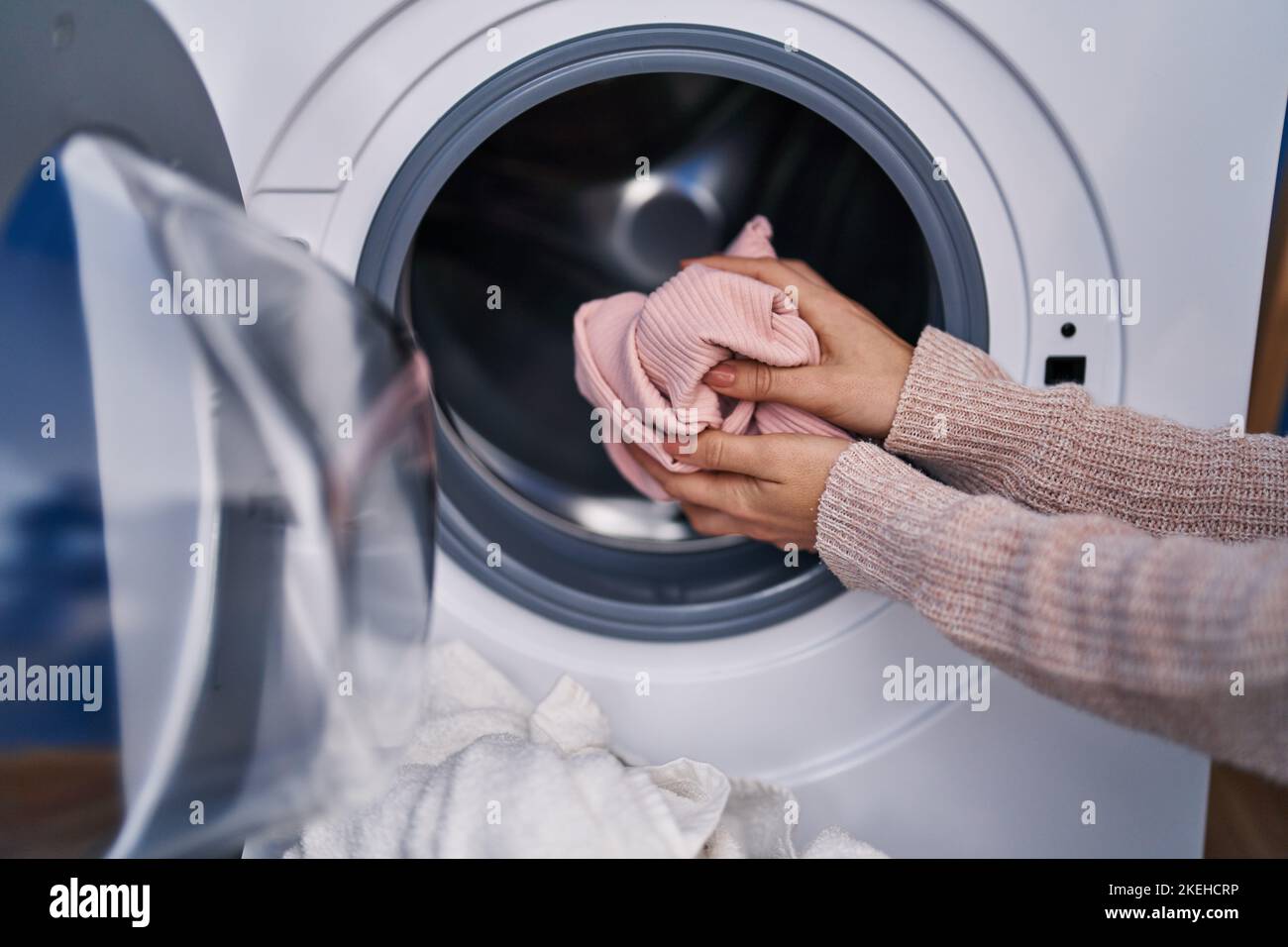 Young woman washing clothes at laundry room Stock Photo - Alamy
