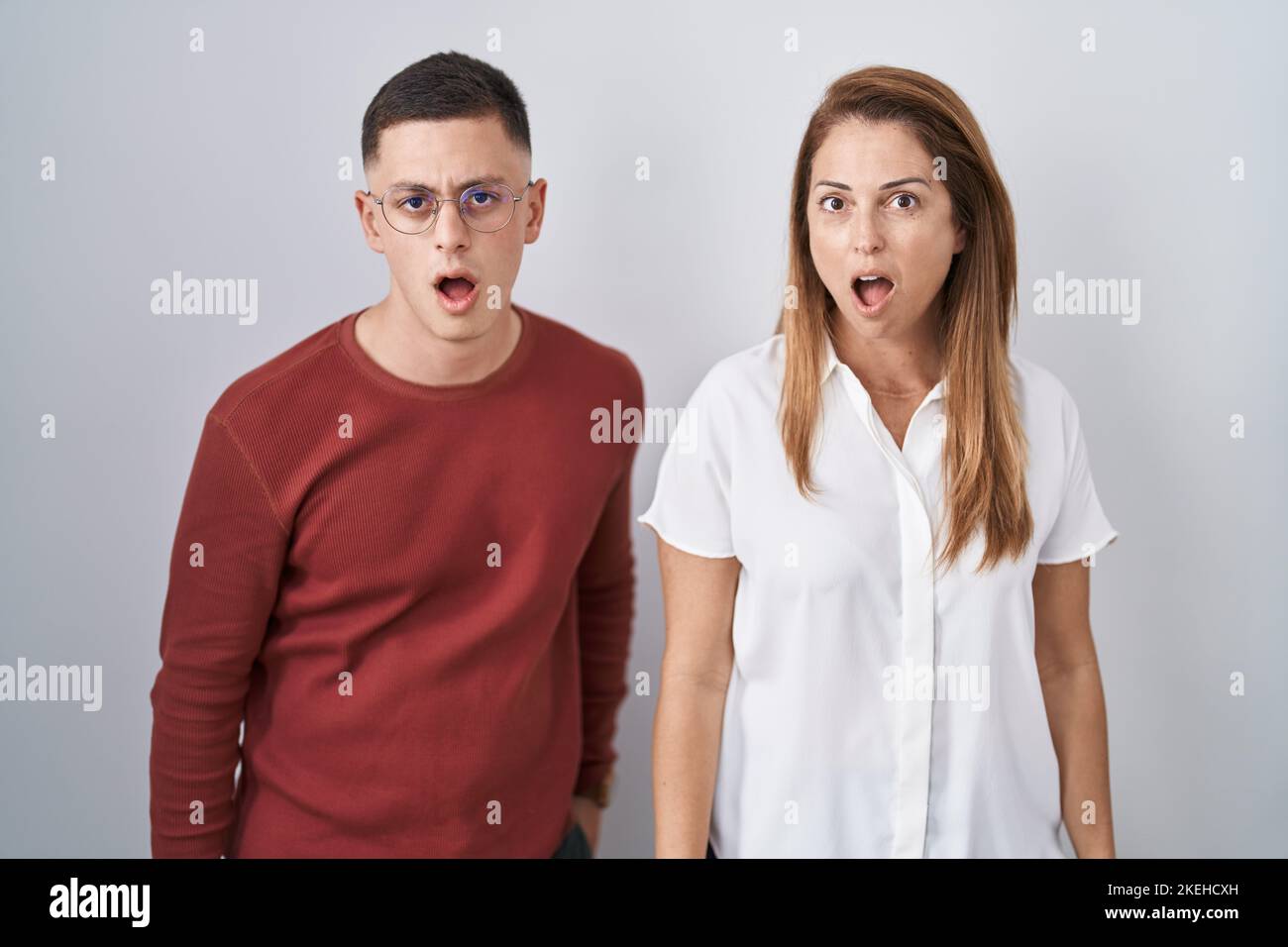 Mother and son standing together over isolated background in shock face ...