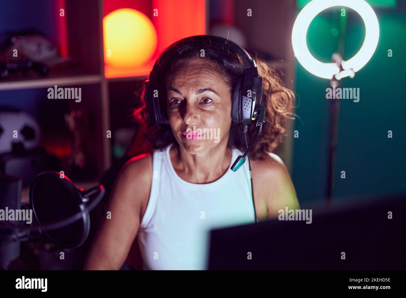 Middle age woman streamer playing video game using computer at gaming ...