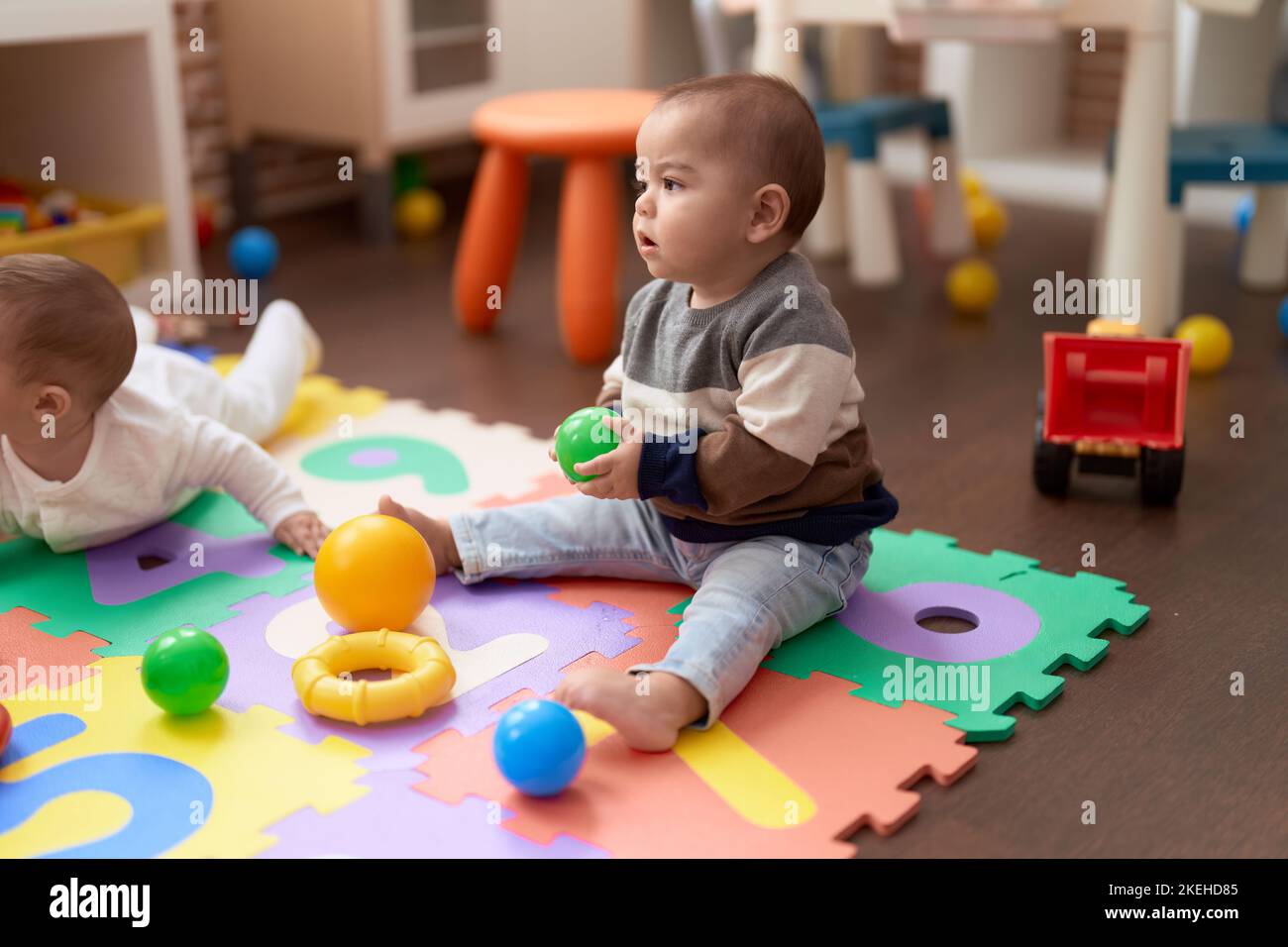 Adorable chinese toddler playing with ball sitting on floor at ...