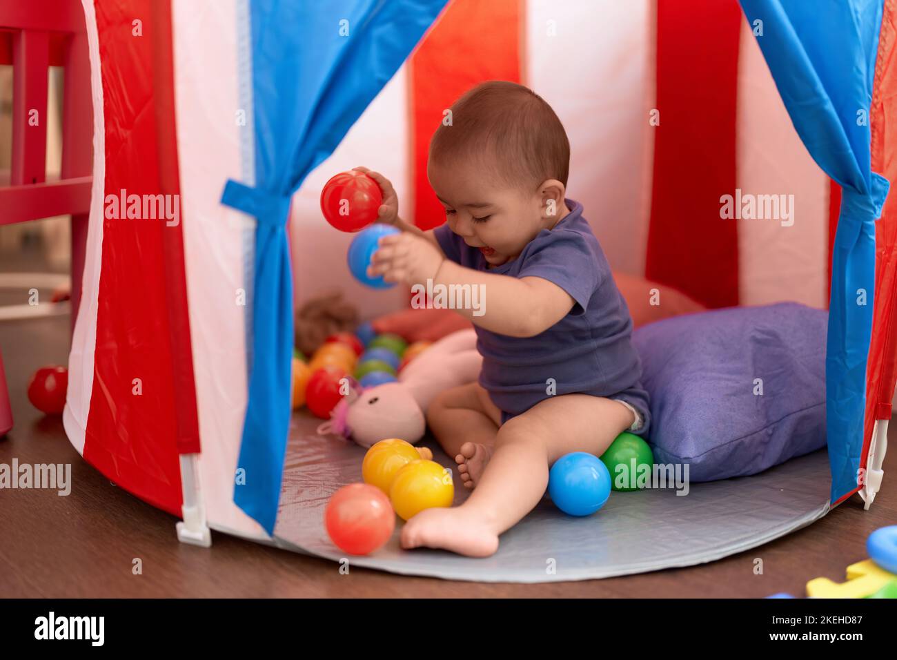 Adorable chinese toddler playing with balls sitting inside of circus ...