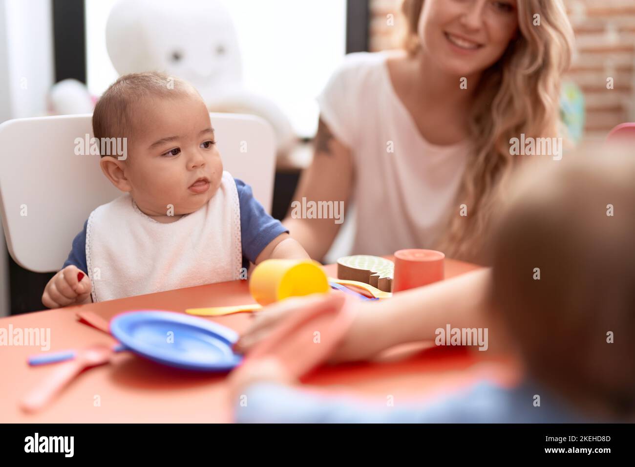 Teacher and preschool student learning to eat sitting on table at ...