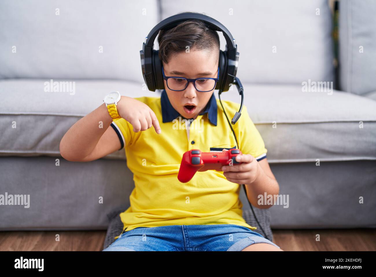 Young hispanic kid playing video game holding controller wearing ...