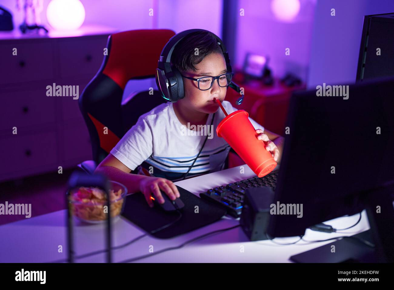 Adorable hispanic boy streamer playing video game drinking beverage at ...