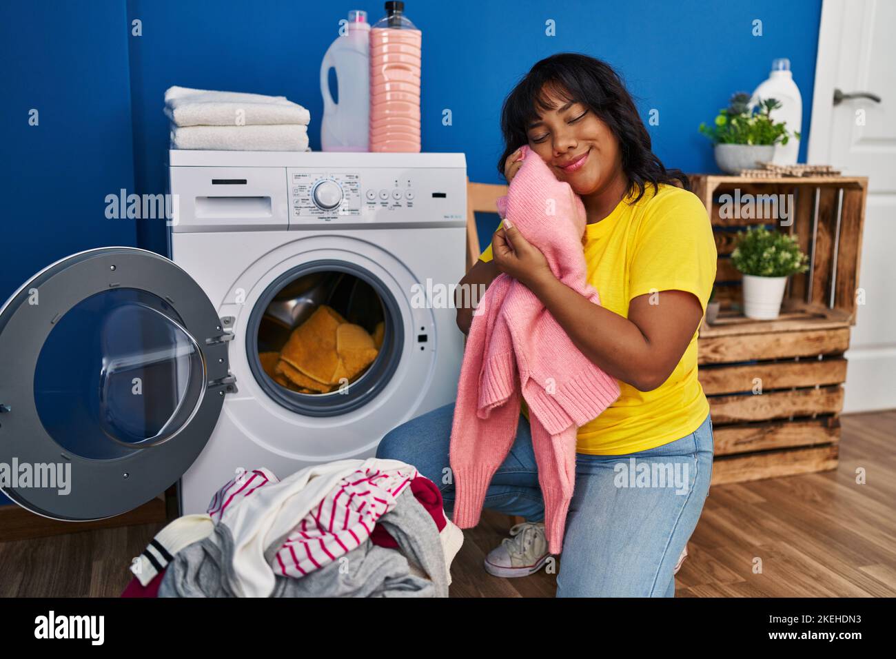 Young beautiful latin woman washing clothes touching face with soft ...