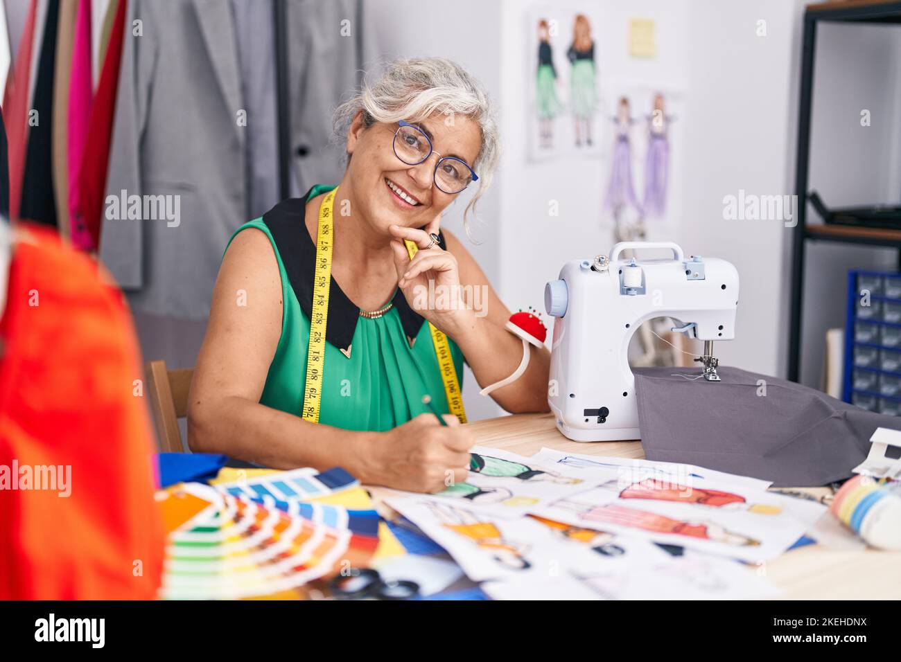 Middle age grey-haired woman tailor smiling confident drawing clothing ...