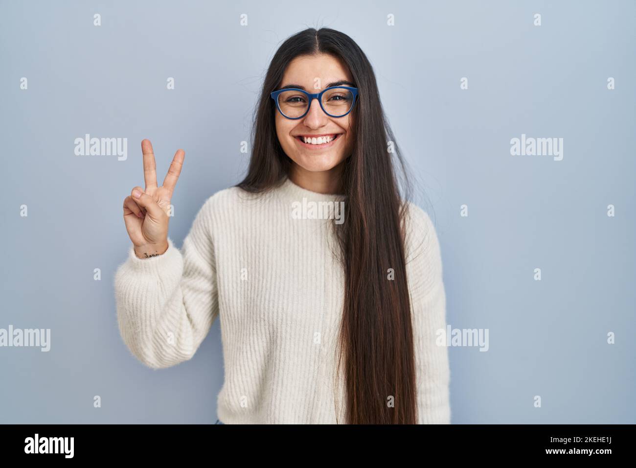 Young hispanic woman wearing casual sweater over blue background ...