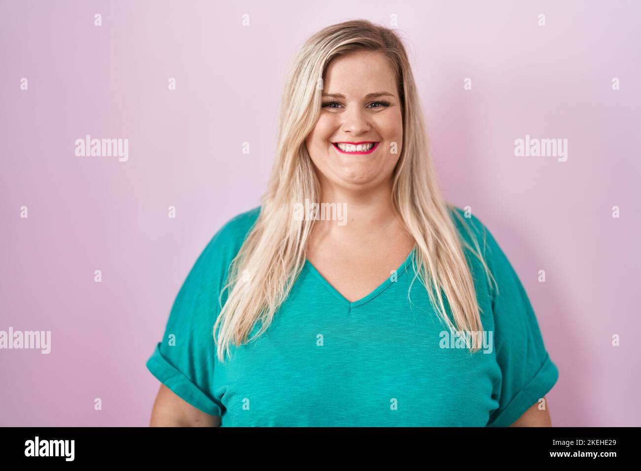Caucasian plus size woman standing over pink background with a happy ...