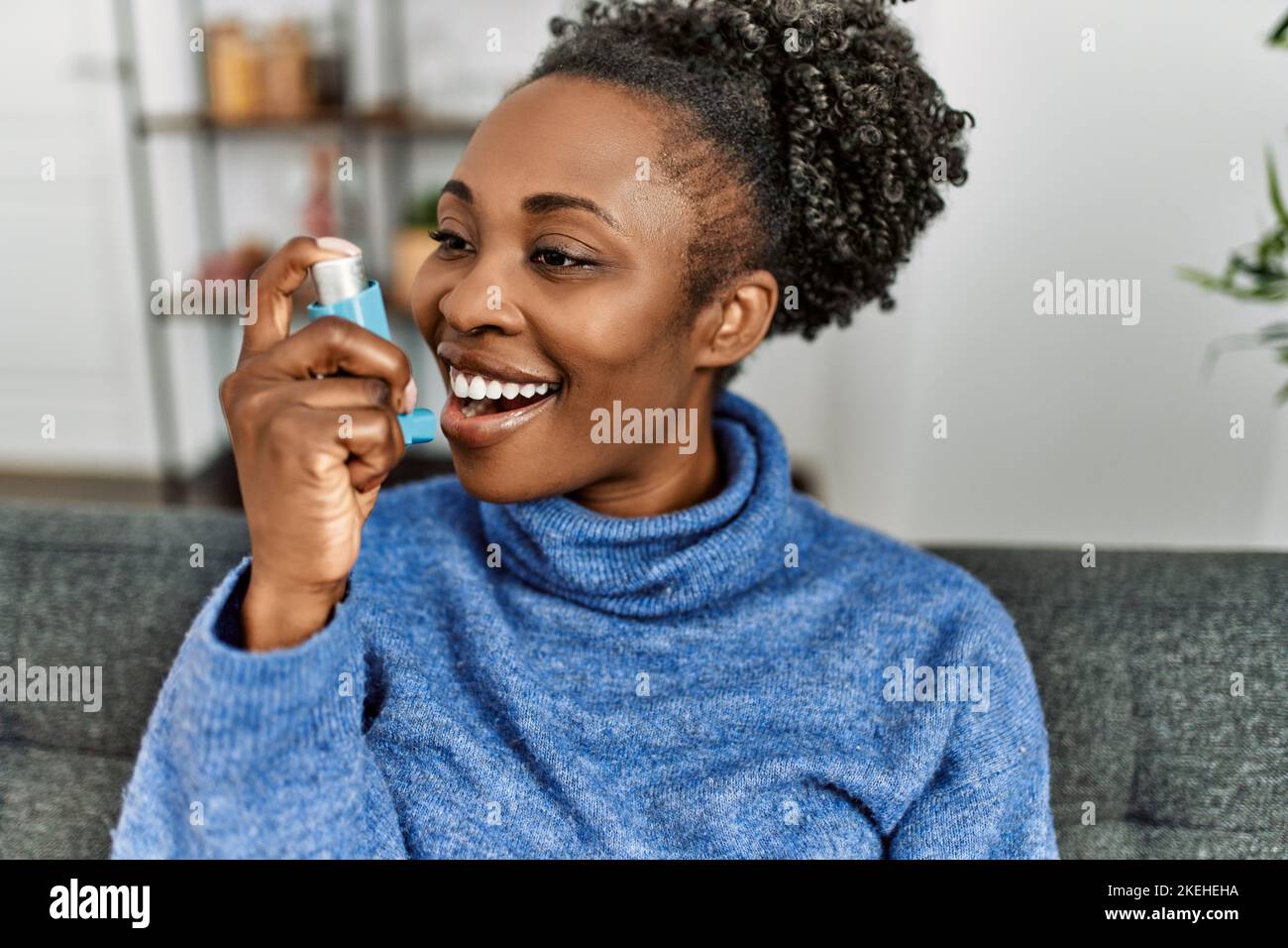 African american woman using inhaler sitting on sofa at home Stock ...