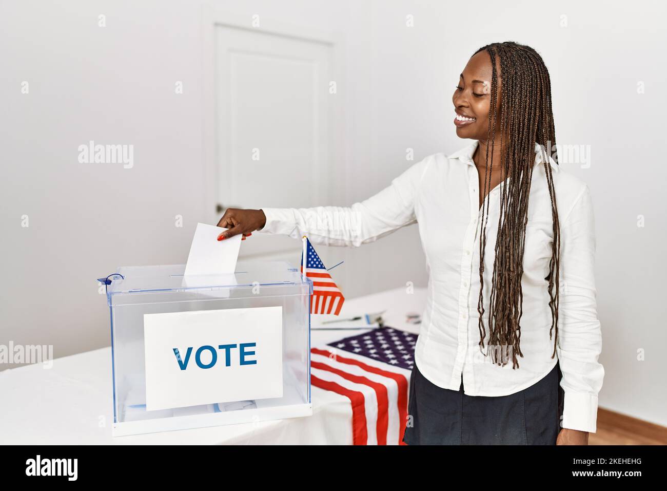 Young african american voter woman putting vote in ballot box at ...