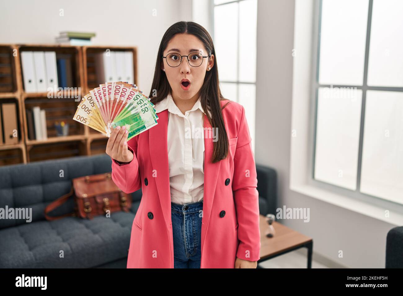 Young latin woman working at consultation office holding money scared ...