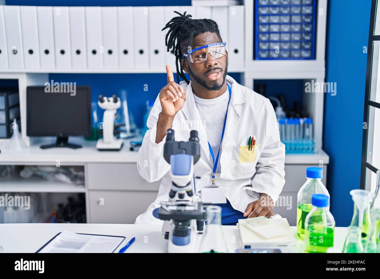 African man with dreadlocks working at scientist laboratory smiling ...
