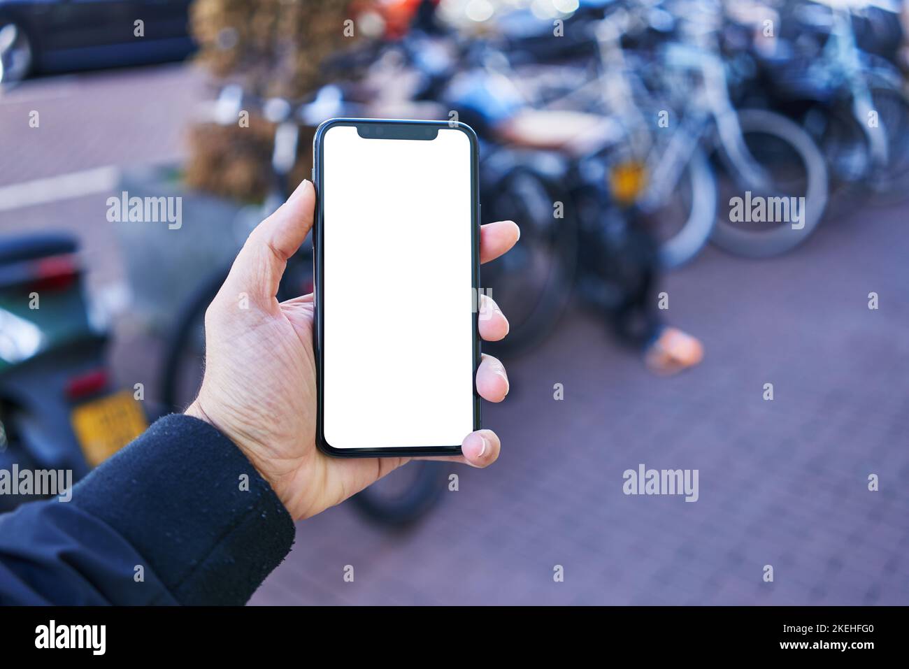 Man holding smartphone showing white blank screen at bike parking Stock ...