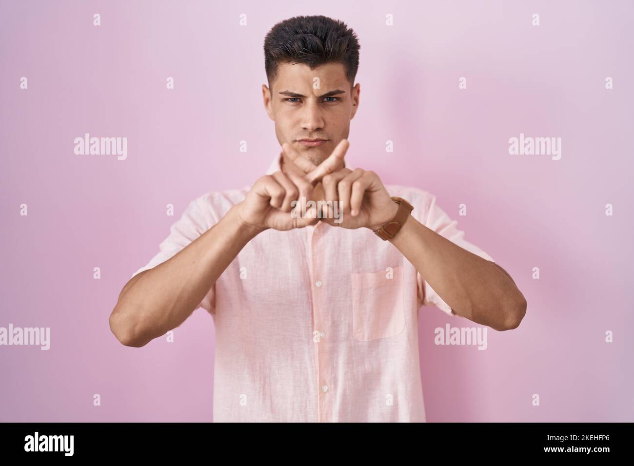 Young hispanic man standing over pink background rejection expression ...