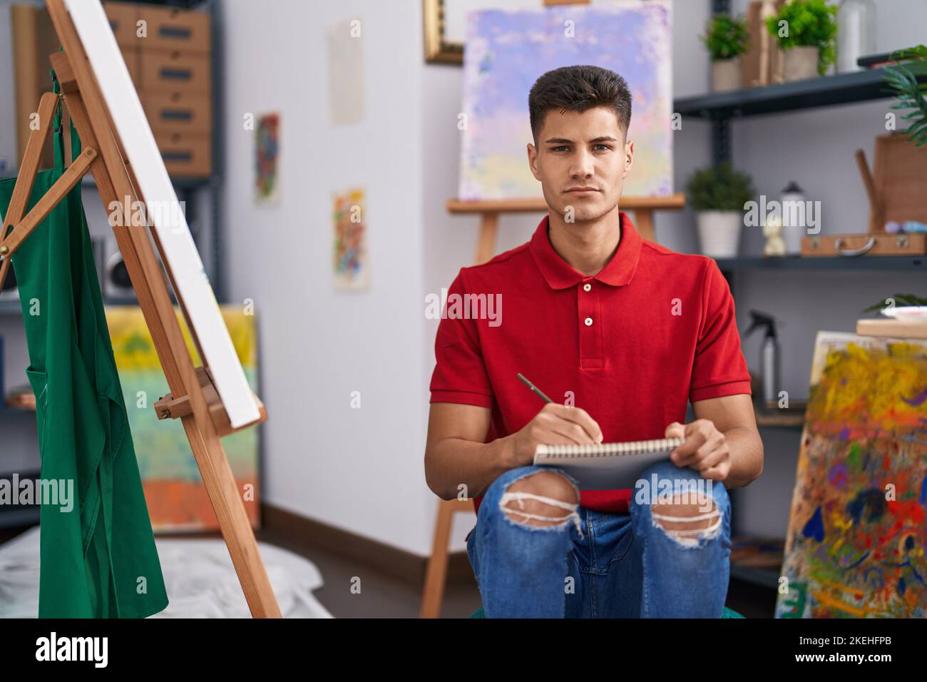 Young hispanic man drawing on art notebook thinking attitude and sober ...