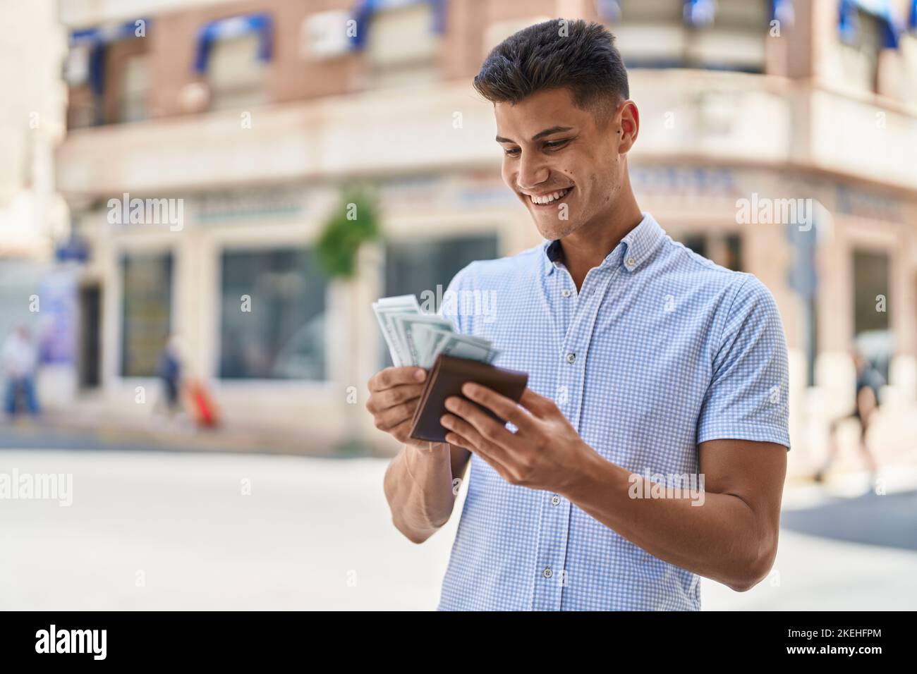 Young hispanic man smiling confident holding wallet with dollars at ...