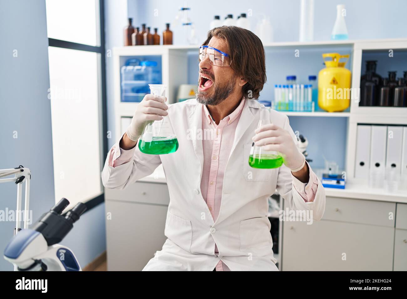 Handsome middle age man working at scientist laboratory pointing with ...