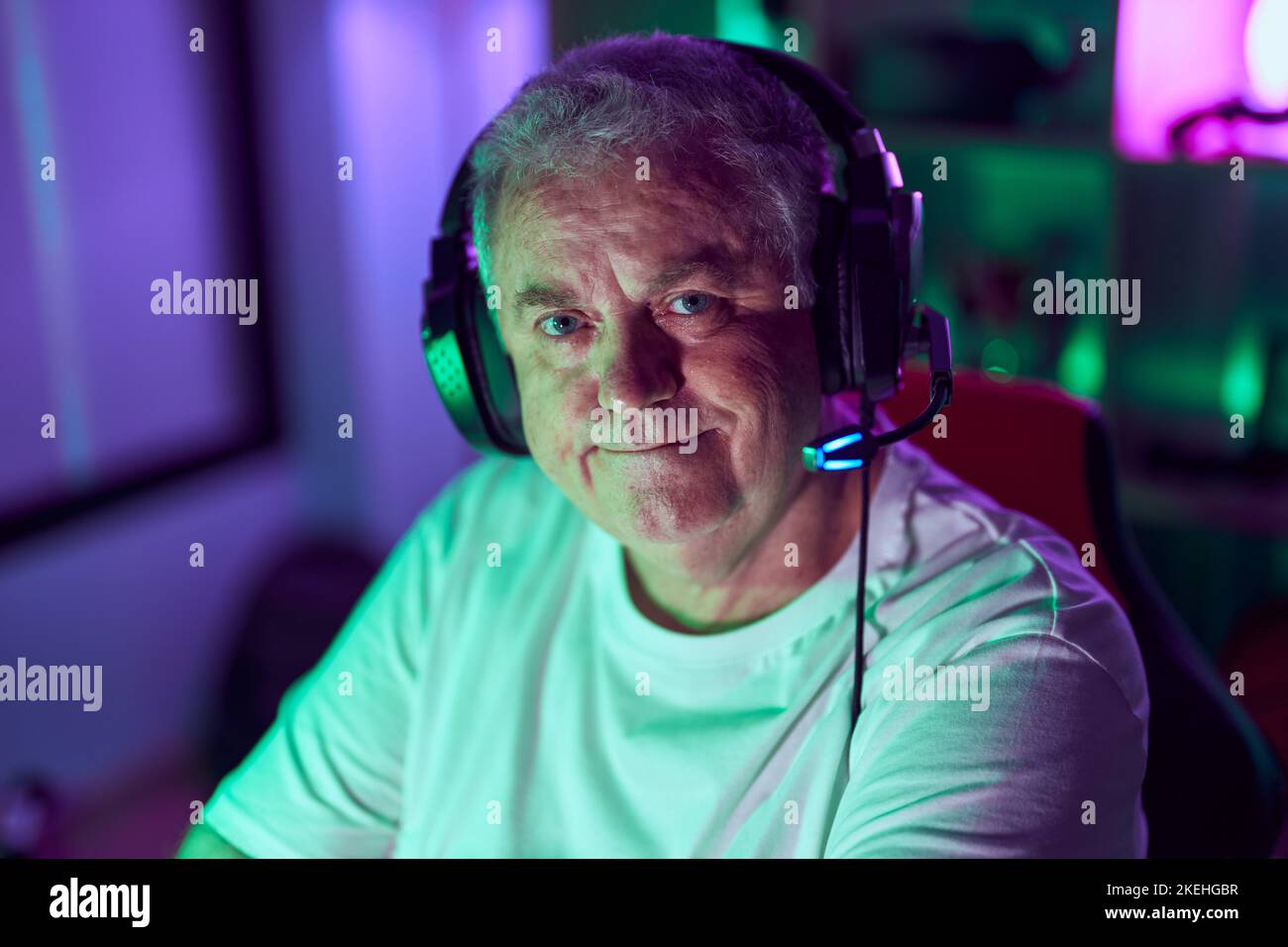 Middle age grey-haired man streamer smiling confident sitting on table ...