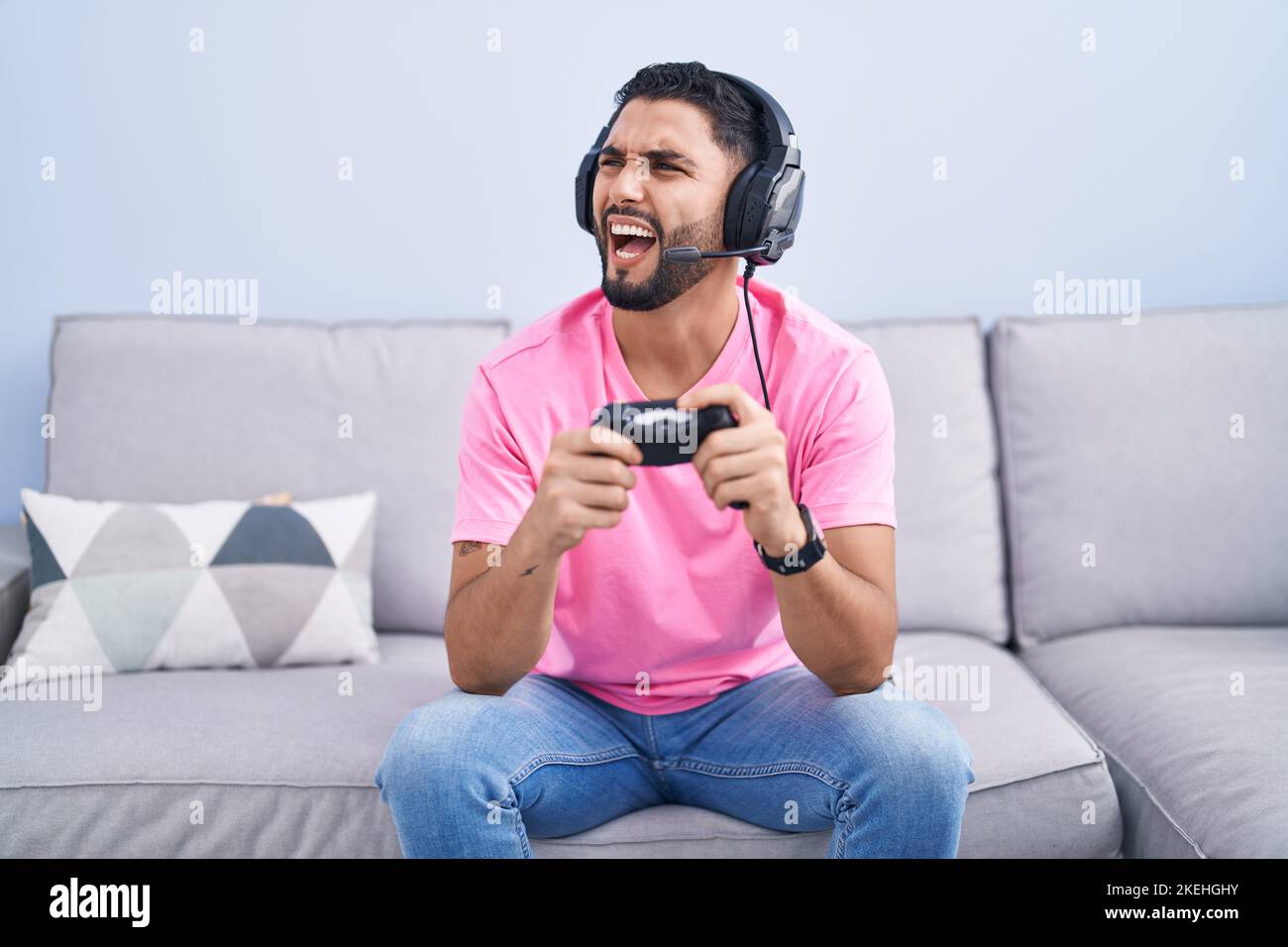 Hispanic young man playing video game holding controller sitting on the ...