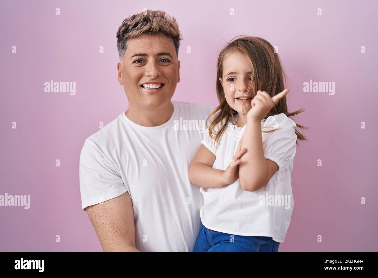 Young father hugging daughter over pink background smiling happy ...