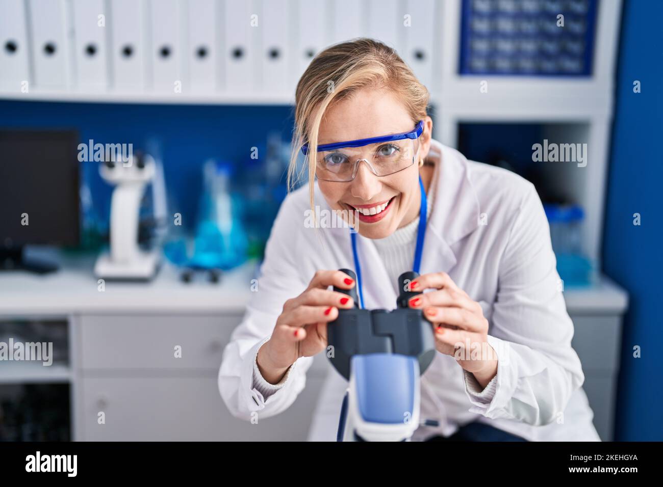 Young blonde woman scientist smiling confident using microscope at laboratory Stock Photo - Alamy