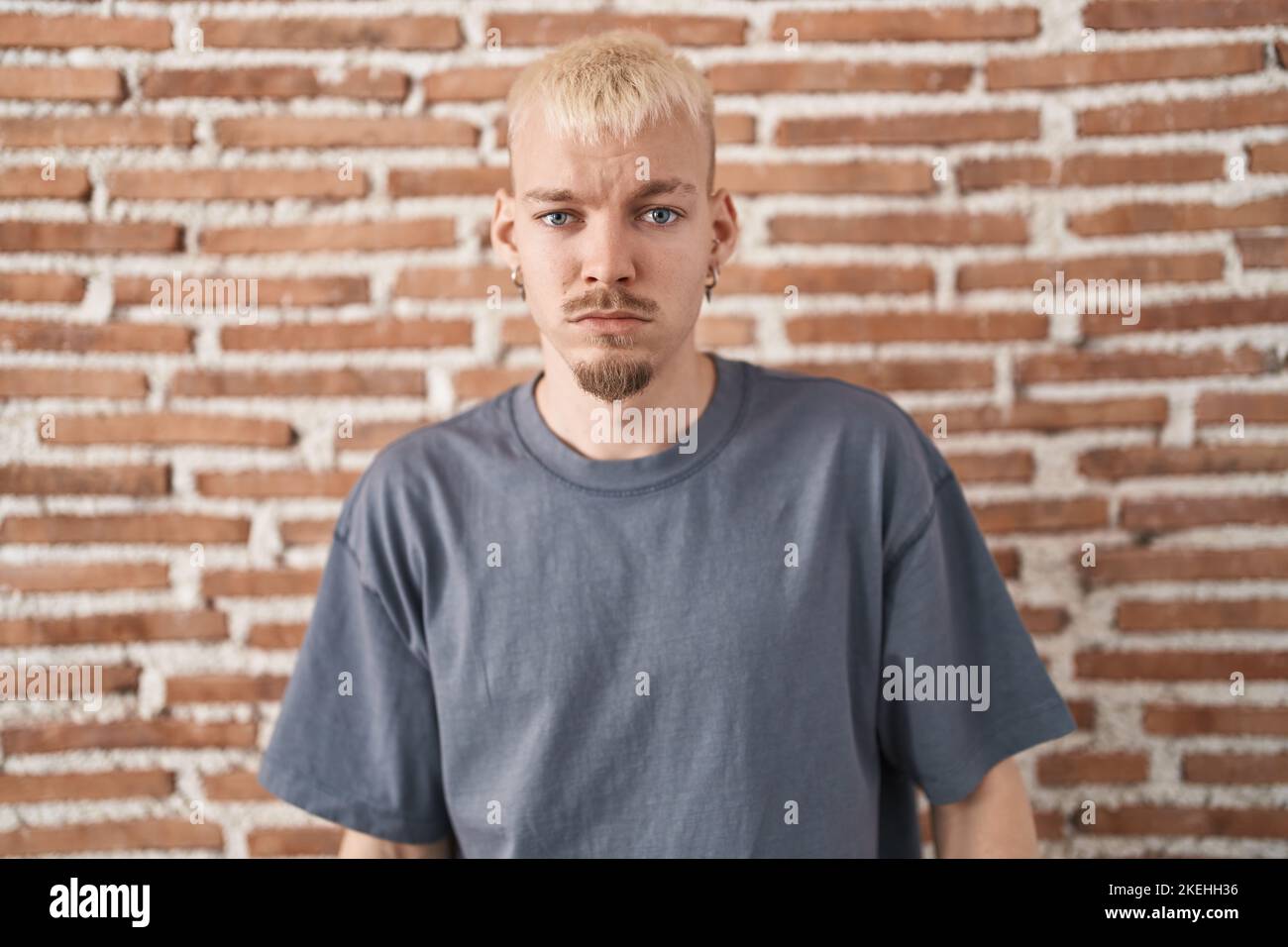 Young caucasian man standing over bricks wall depressed and worry for ...