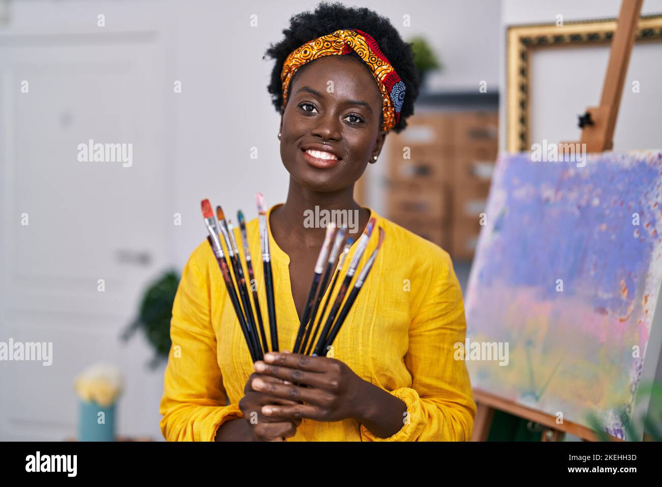 Young african american woman smiling confident holding paintbrushes at ...