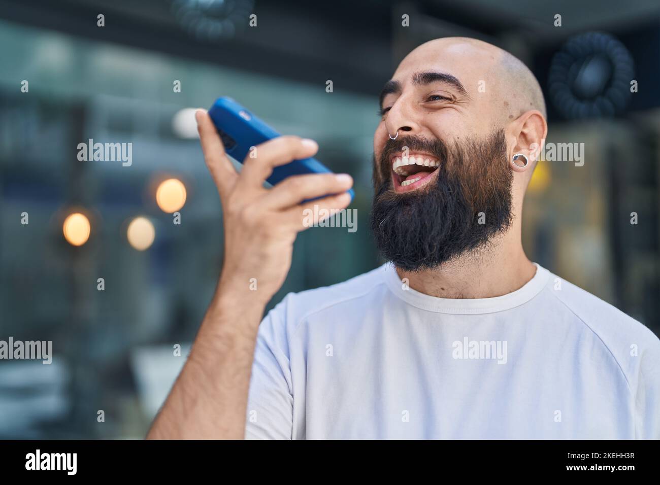 Young bald man smiling confident talking on the smartphone at street ...
