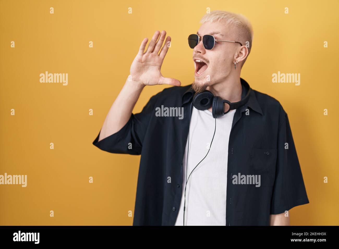 Young caucasian man wearing sunglasses standing over yellow background ...