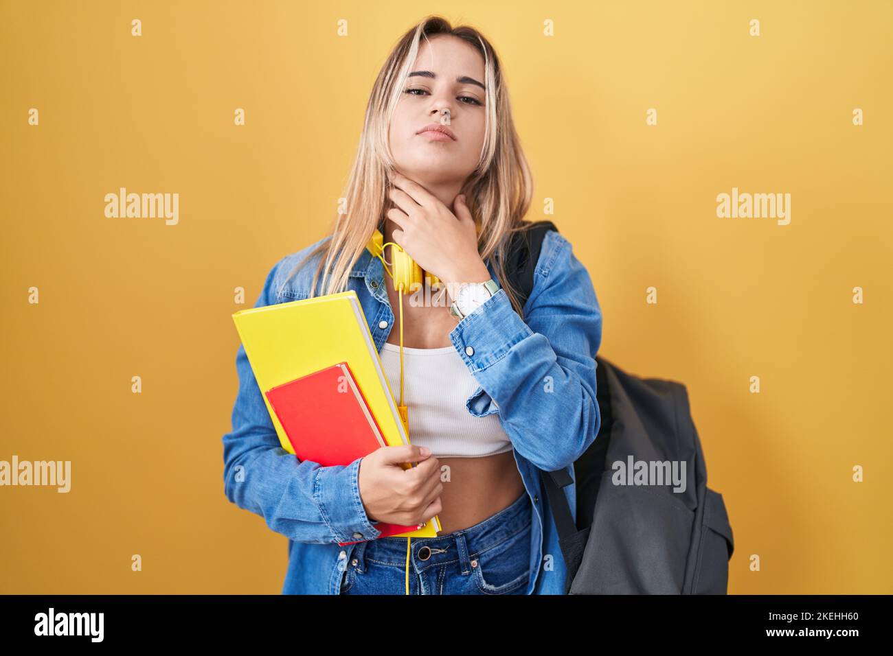 Young blonde woman wearing student backpack and holding books touching ...