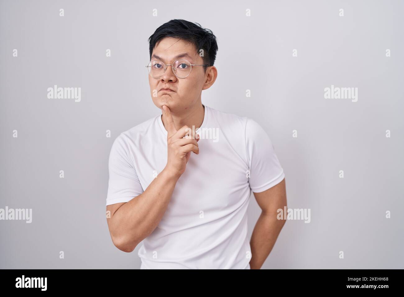 Young asian man standing over white background thinking concentrated ...
