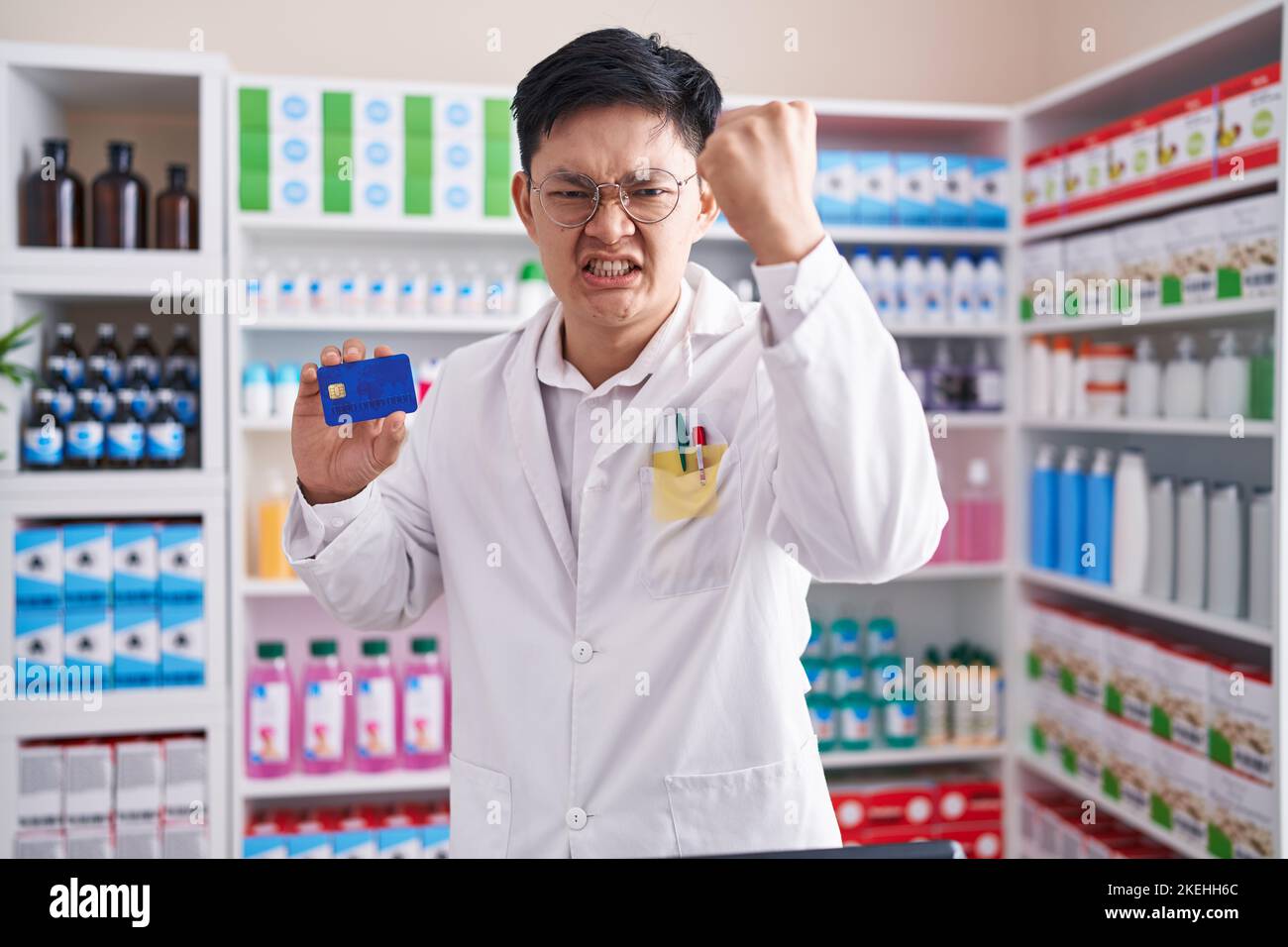 Young asian man working at pharmacy drugstore holding credit card ...