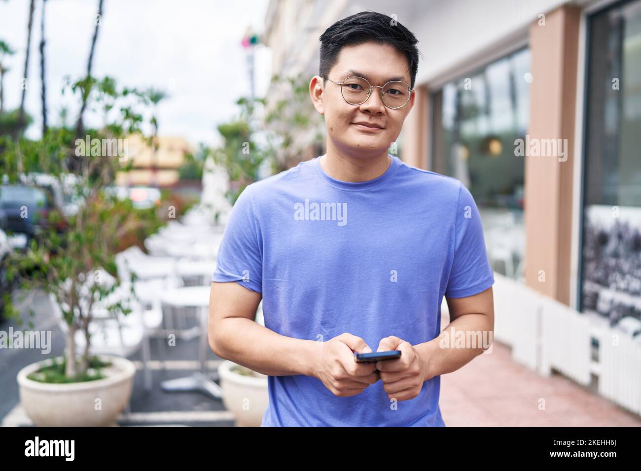 Young chinese man smiling confident using smartphone at coffee shop ...