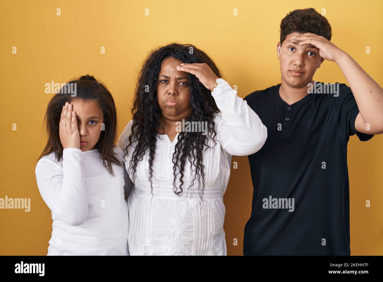Family of mother, daughter and son standing over yellow background ...
