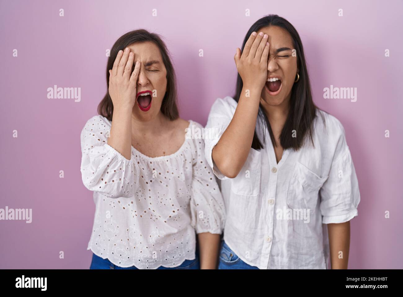 Hispanic mother and daughter together yawning tired covering half face ...