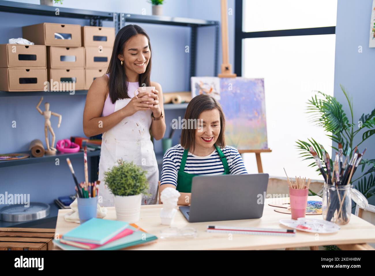 Two women artists using laptop drinking coffee at art studio Stock ...
