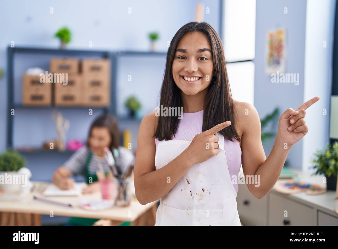 Young woman at art studio smiling and looking at the camera pointing ...