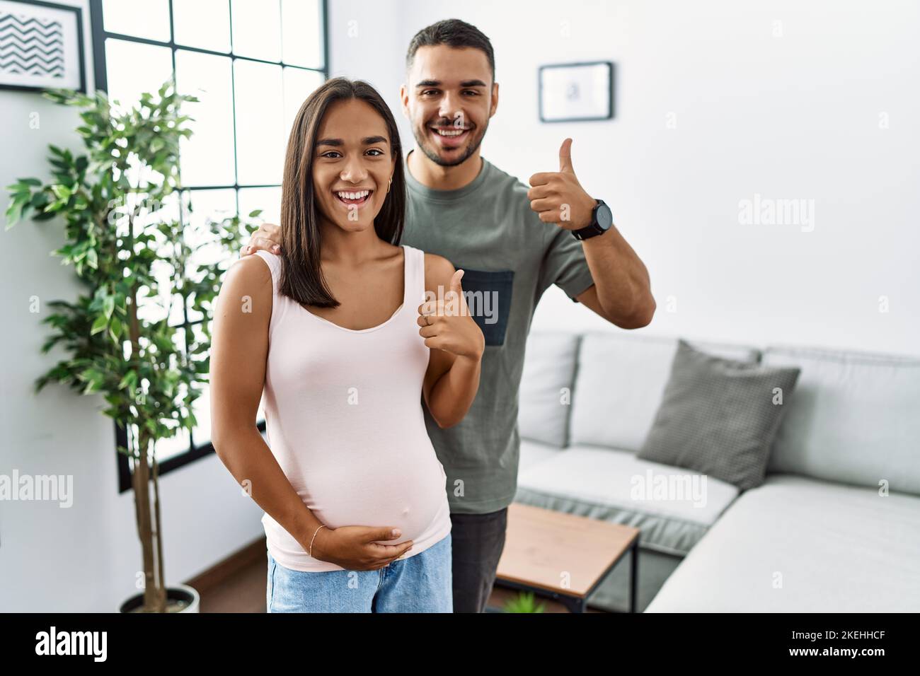 Young interracial couple expecting a baby, touching pregnant belly ...