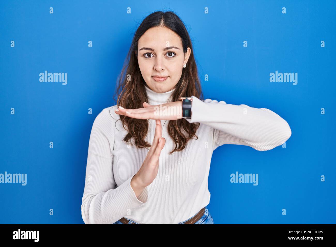 Young hispanic woman standing over blue background doing time out ...